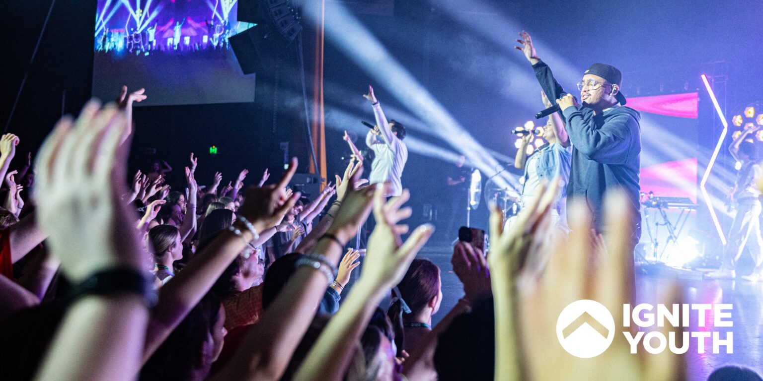 Young people raise their hands in worship - CathNews